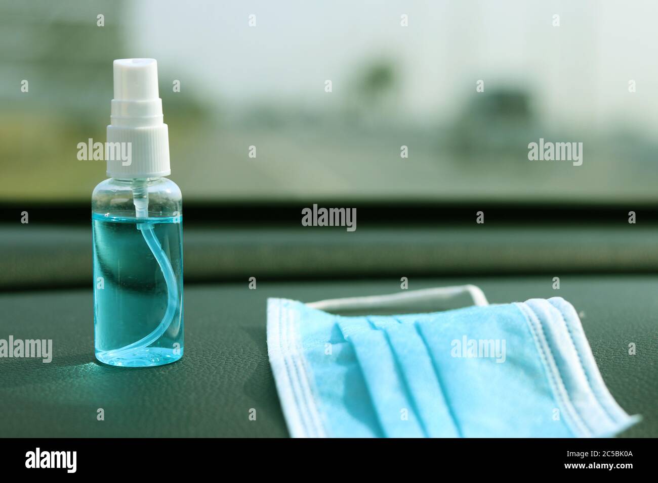 Medical face mask and hand sanitizer spray placed on car console ...