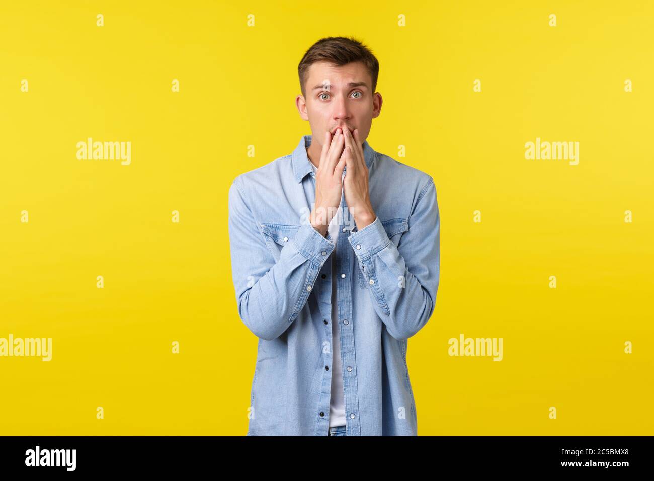 Shocked and worried blond man looking concerned at camera, touching ...