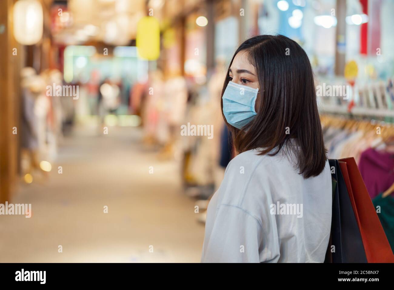 young woman shopping with bag at mall and her wearing medical mask for ...