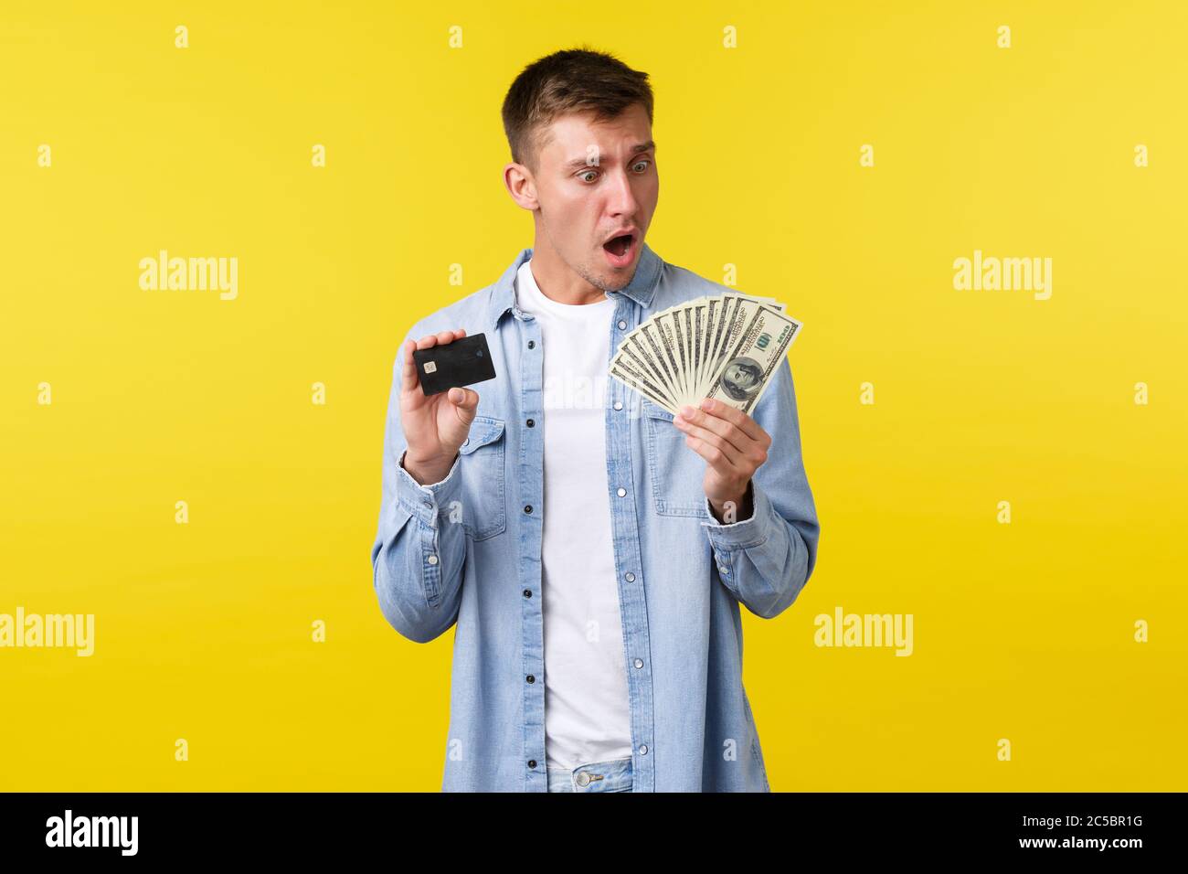 Overwhelmed and shocked young handsome blond guy looking at money with ...