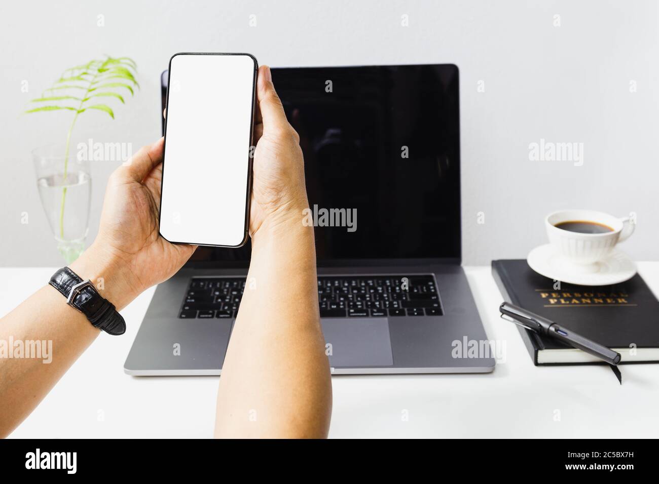Man hands holding mobile phone with laptop computer on table Stock ...