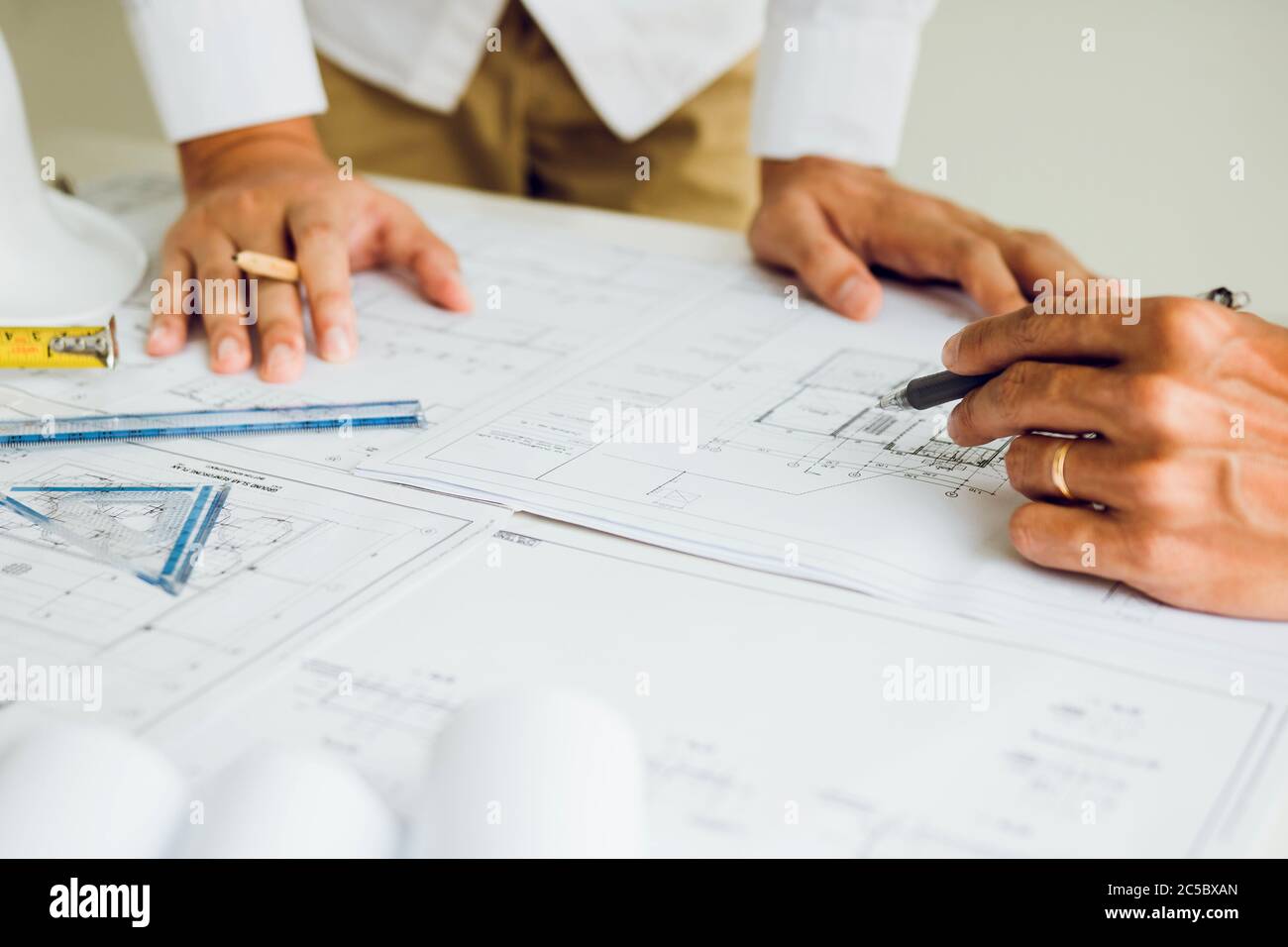 Two partnership architects or engineering working with blueprints and ...