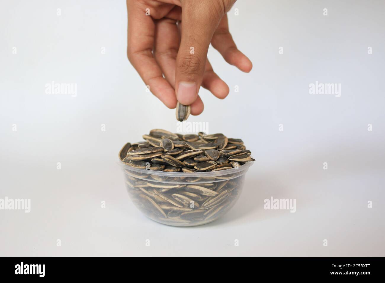 Hand pick Sunflower seeds on transparent bowl isolated on white ...