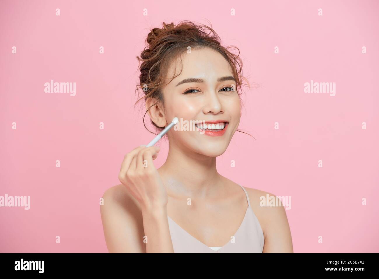 Close-up of a young cute girl holding brush in her hand and applying ...