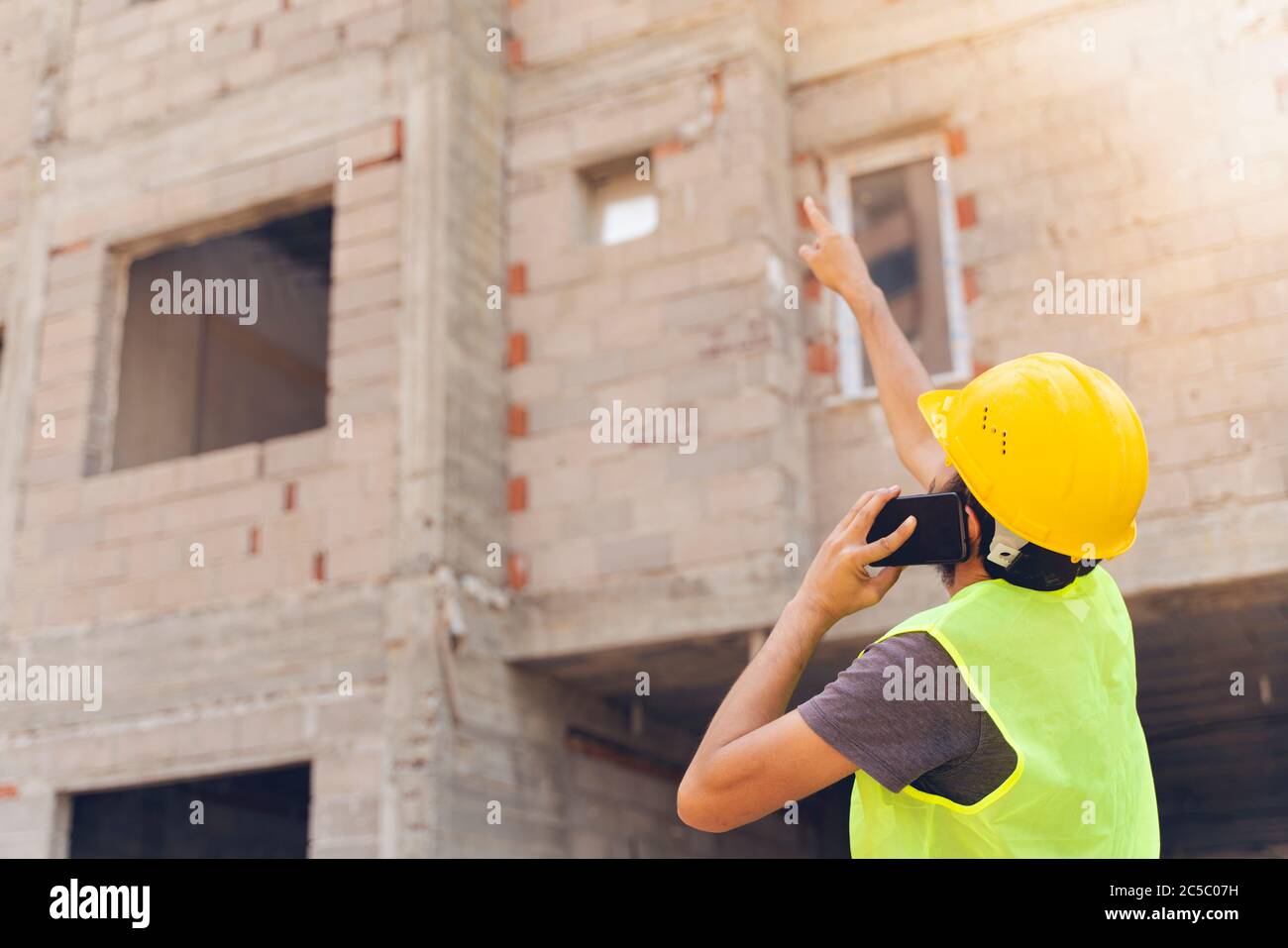 Construction engineer pointing with finger at building under ...
