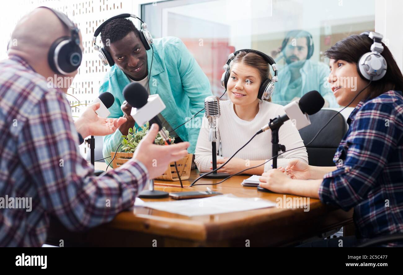 Positive male and female radio presenters talking with guest in sound ...