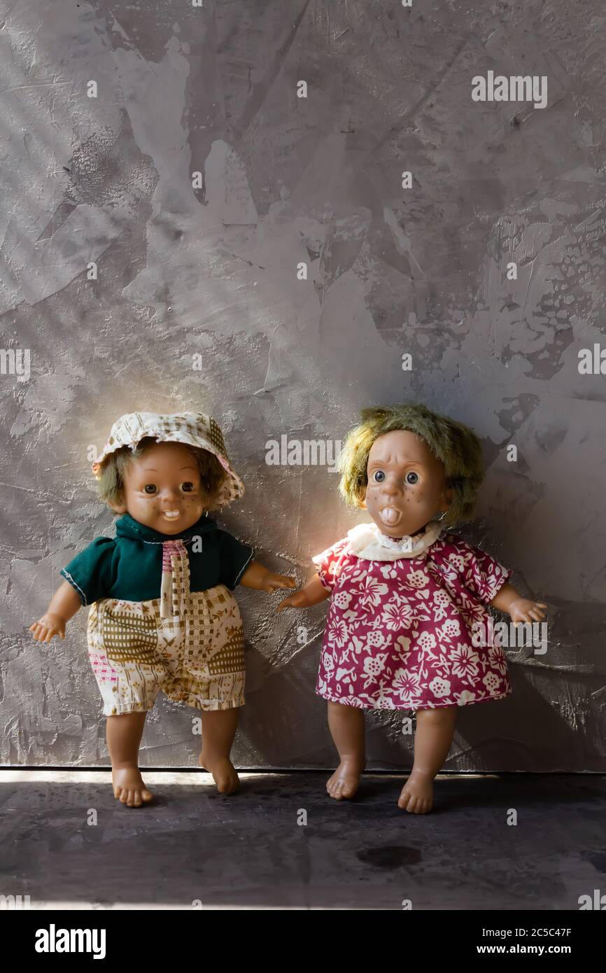 Old, scary, ugly dolls in front of concrete wall Stock Photo - Alamy