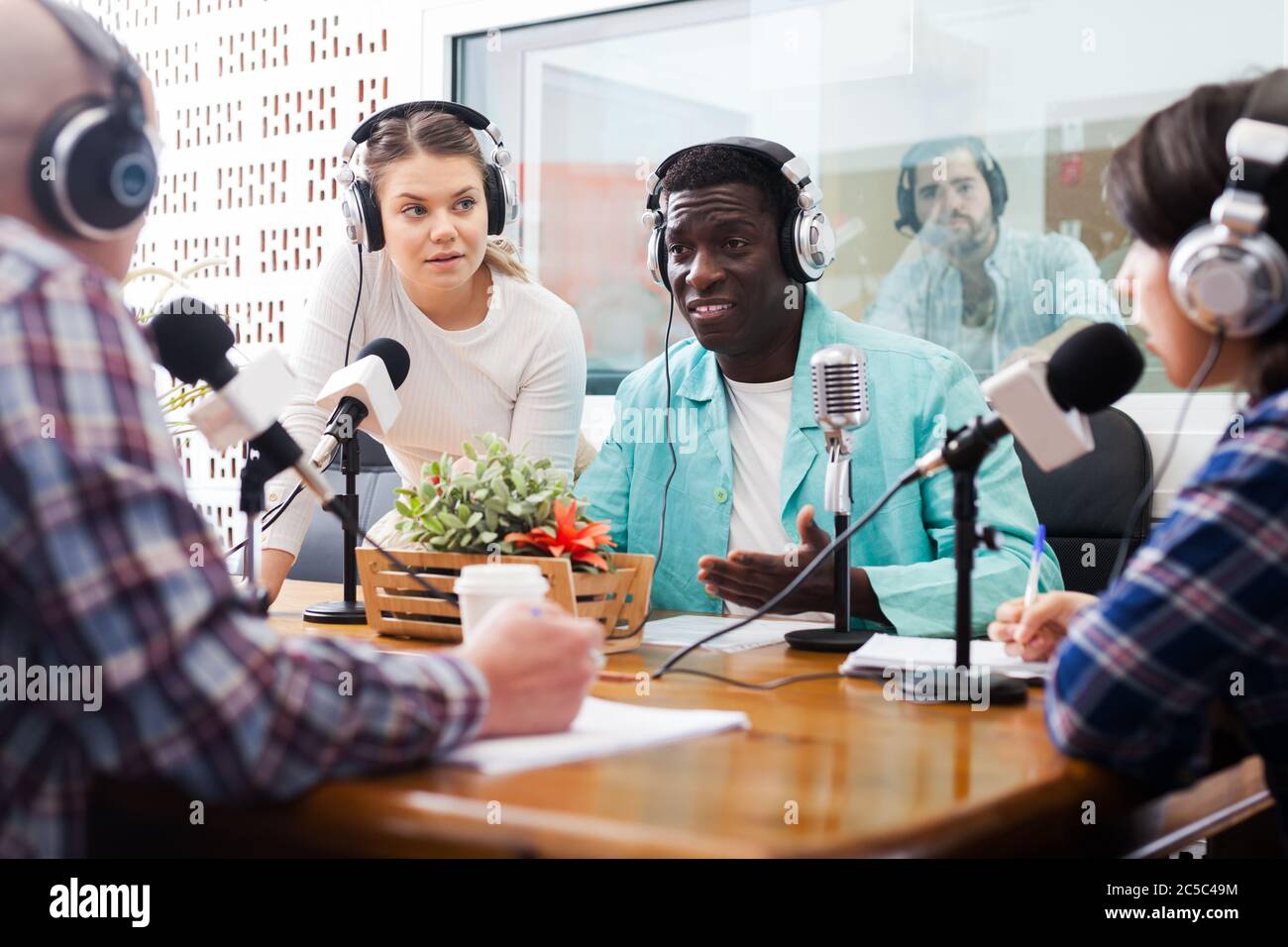 Positive male and female radio presenters discussing with guest in ...