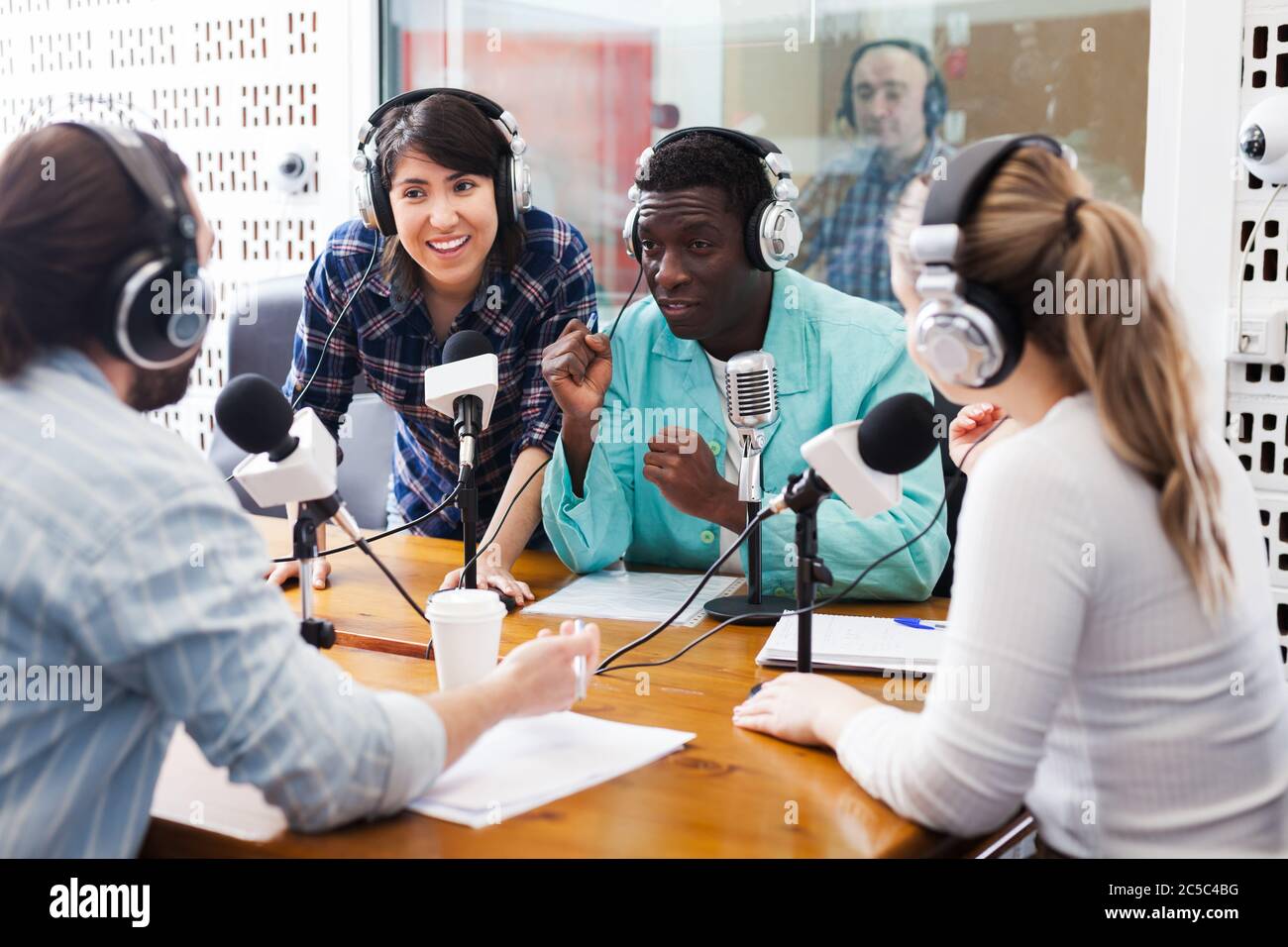 Positive male and female radio hosts discussing with guests in studio ...