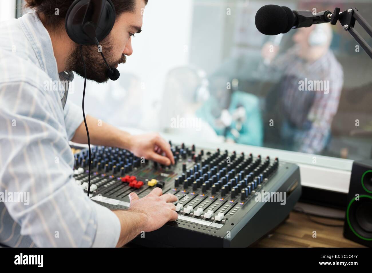 Focused bearded man engaged in sound engineering, working at audio ...