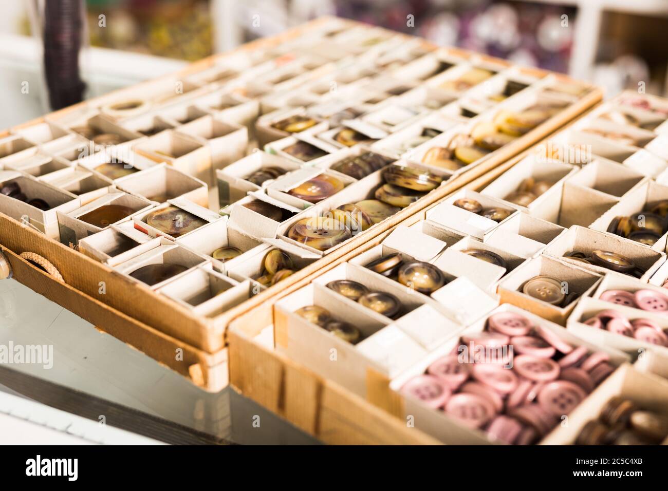 Various flat buttons for clothes in carton boxes on counter in sewing ...