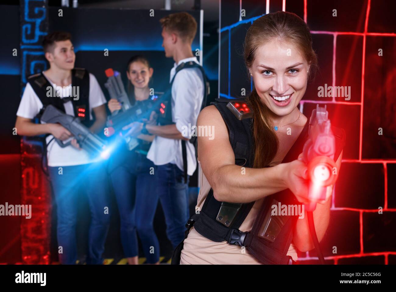 Smiling girl with laser pistol during enjoying laser tag game with her ...