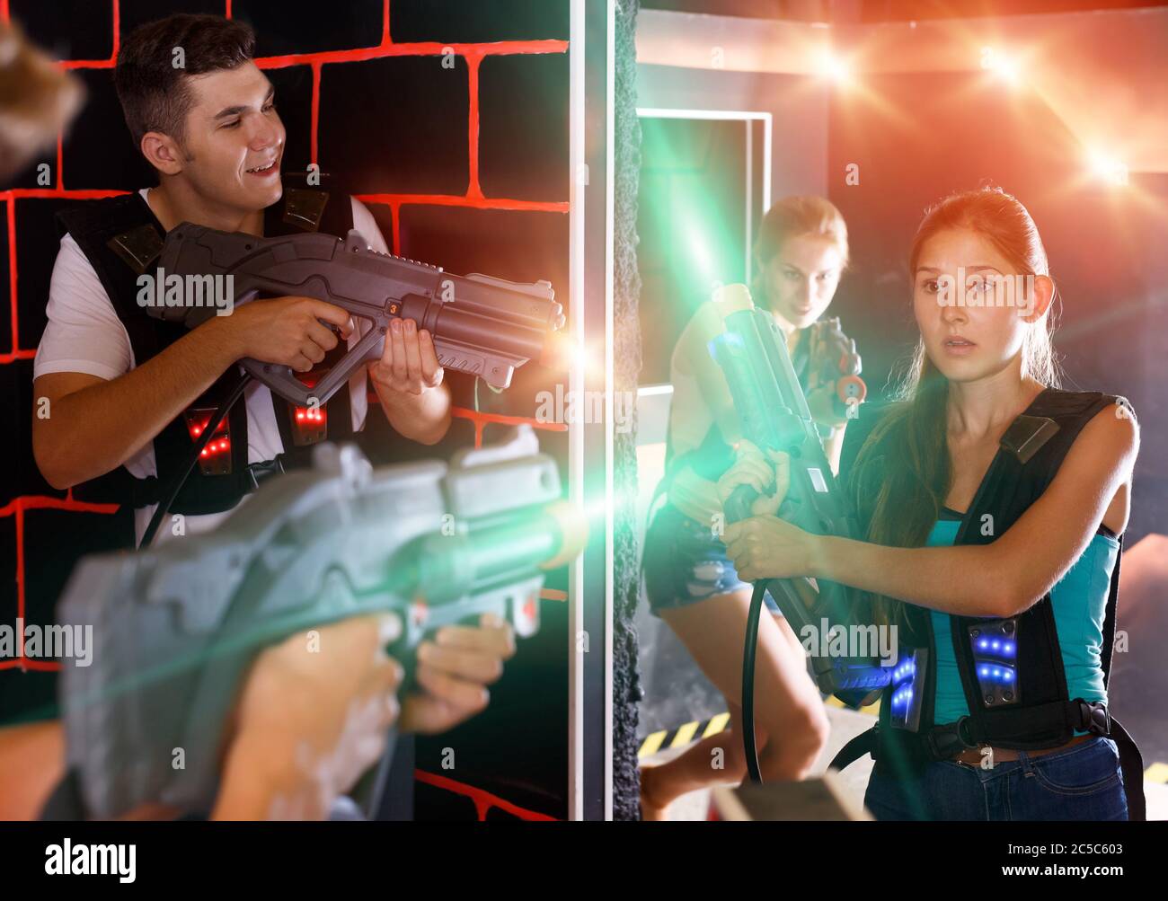 Cheerful Laser tag players young mens and womens playing in teams in ...