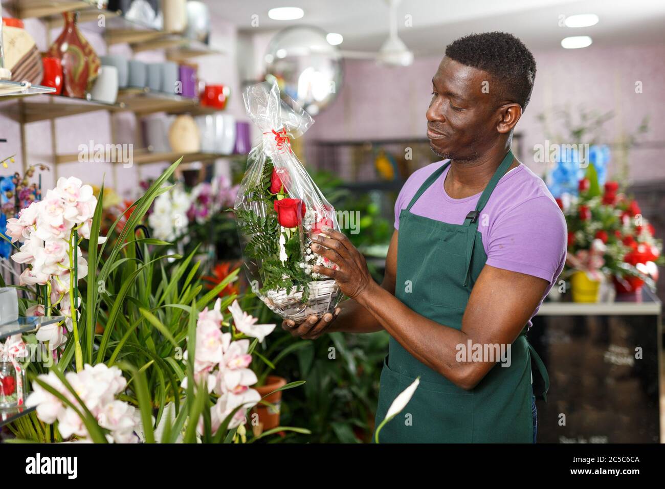 Focused African American man wearing in apron working in flower shop ...