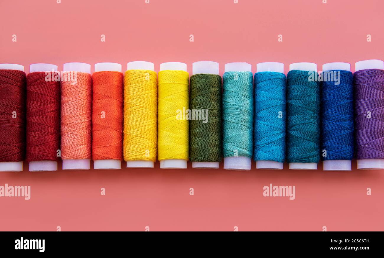 Spools of thread on the colors of the rainbow on a pink background ...