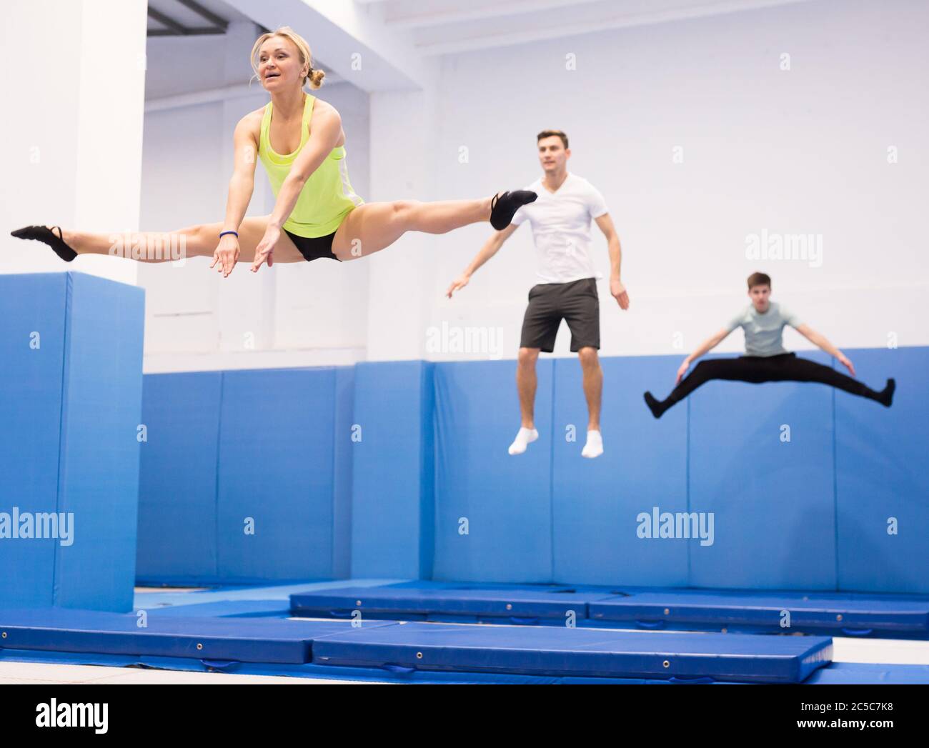 Female gymnast jumping on professional trampoline, practicing middle ...