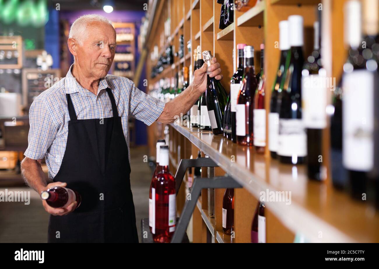 Confident elderly cheerful positive salesman of wine house arranging ...