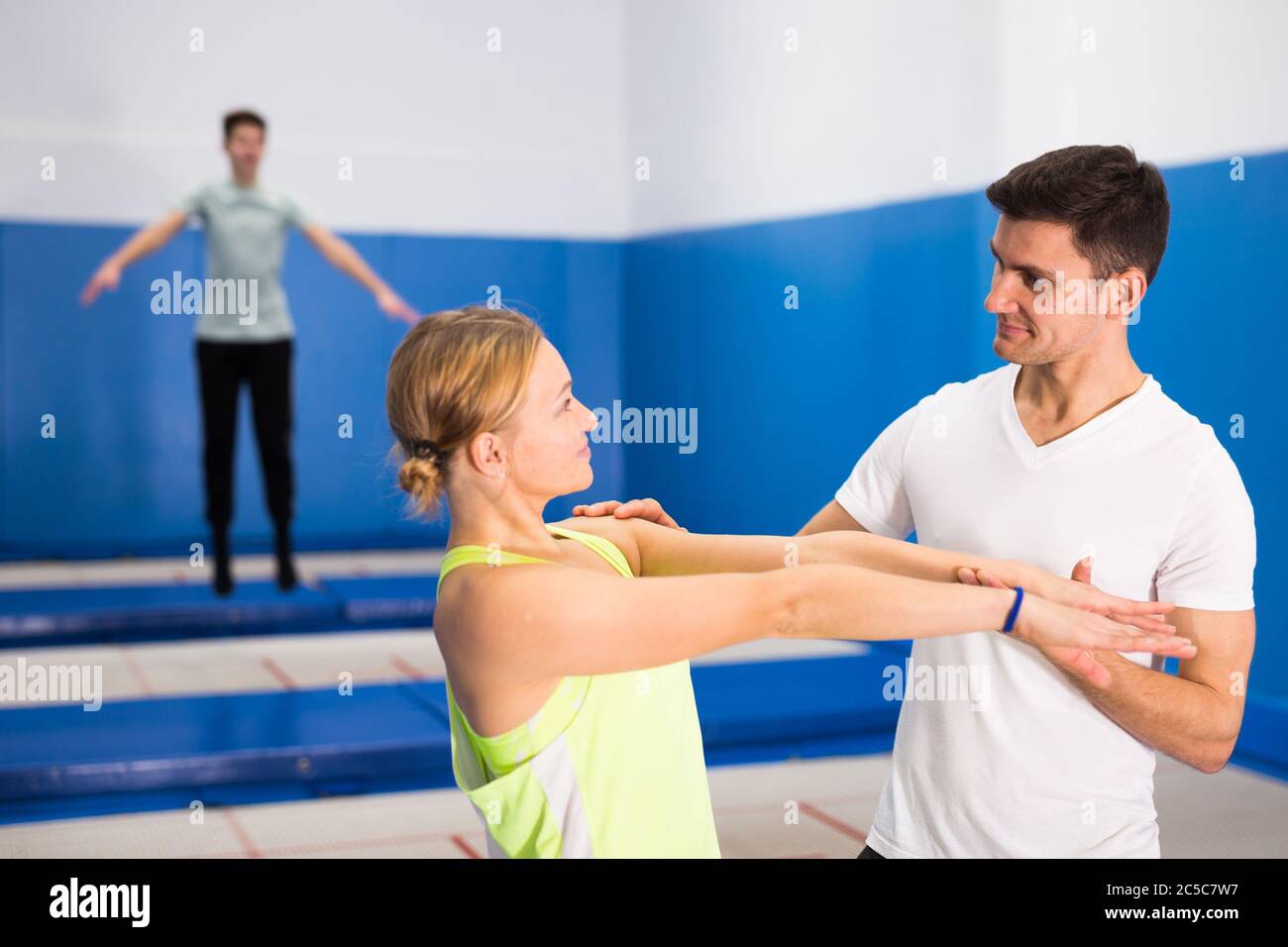 Portrait of man coach showing young woman jumping movements during ...
