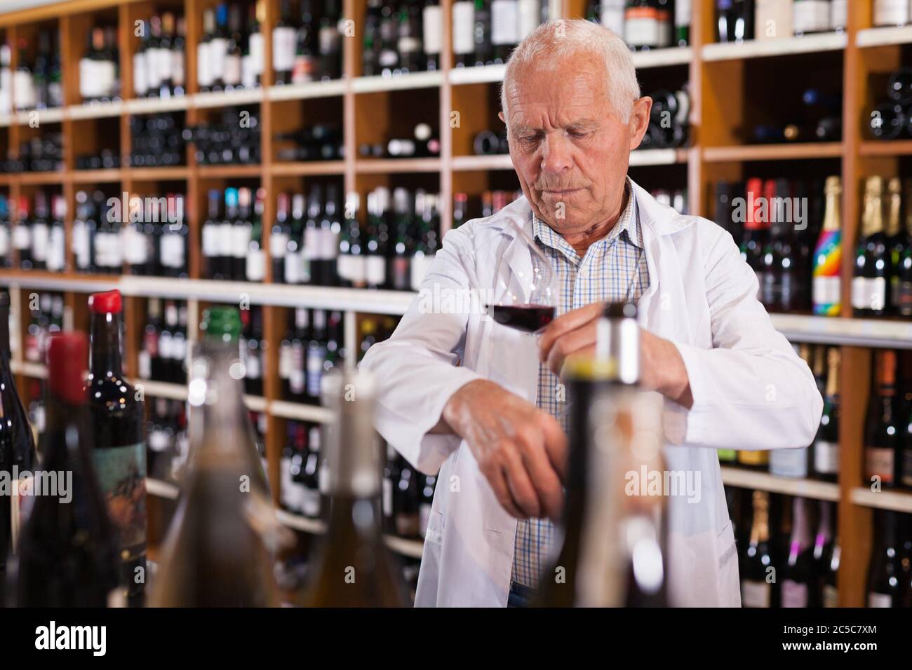 Portrait of senior man professional sommelier tasting red wines in ...