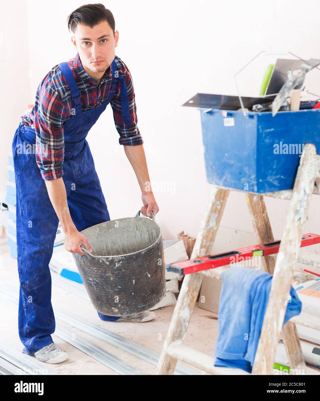 Worker repairing room and looking for necessary tool Stock Photo - Alamy