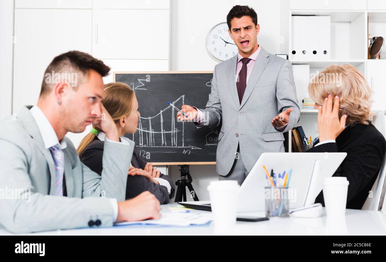 Businessman feeling angry to coworkers in office, pointing at diagrams ...