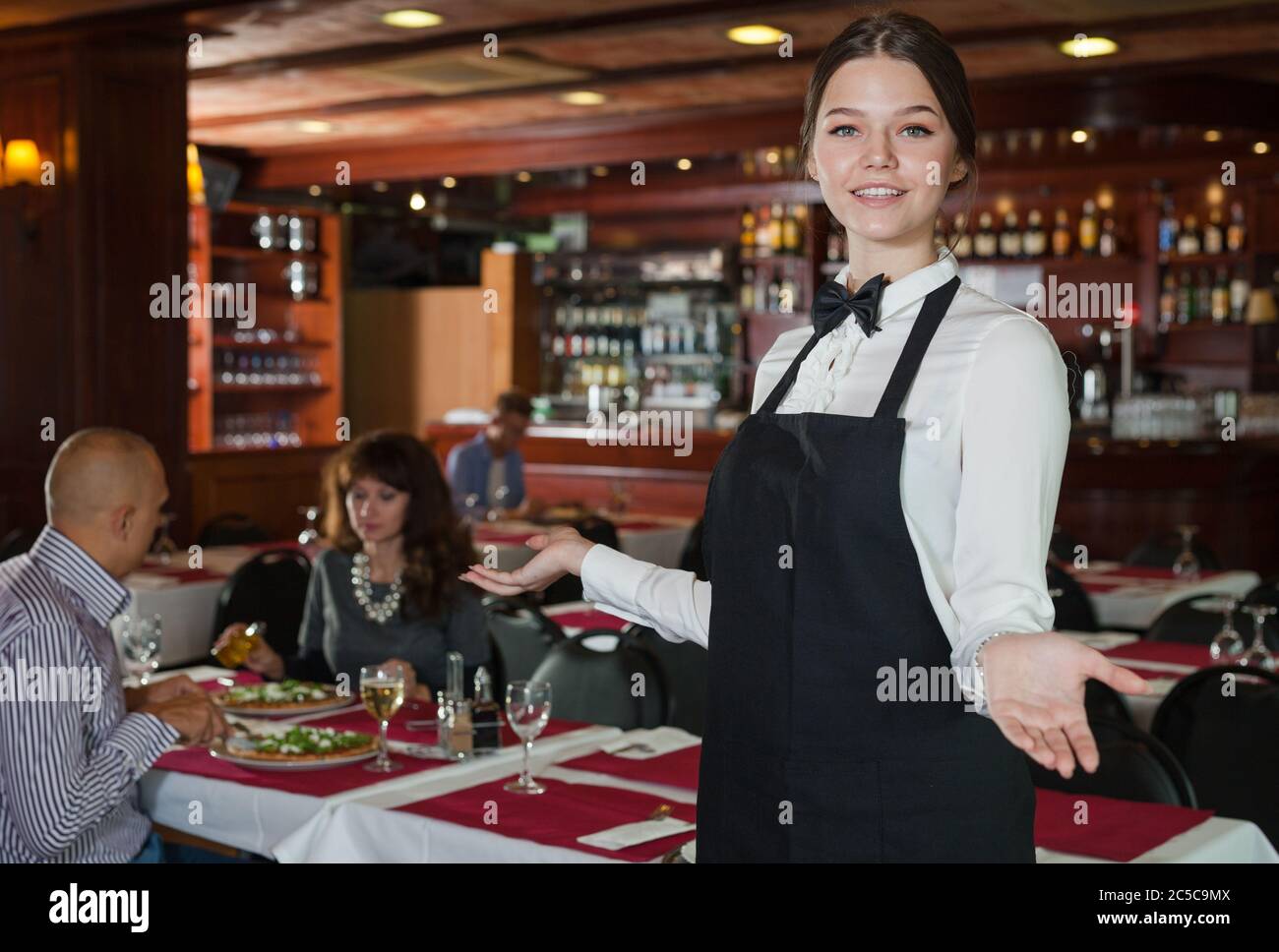 Attractive young waitress meeting guests in restaurant hall Stock Photo ...