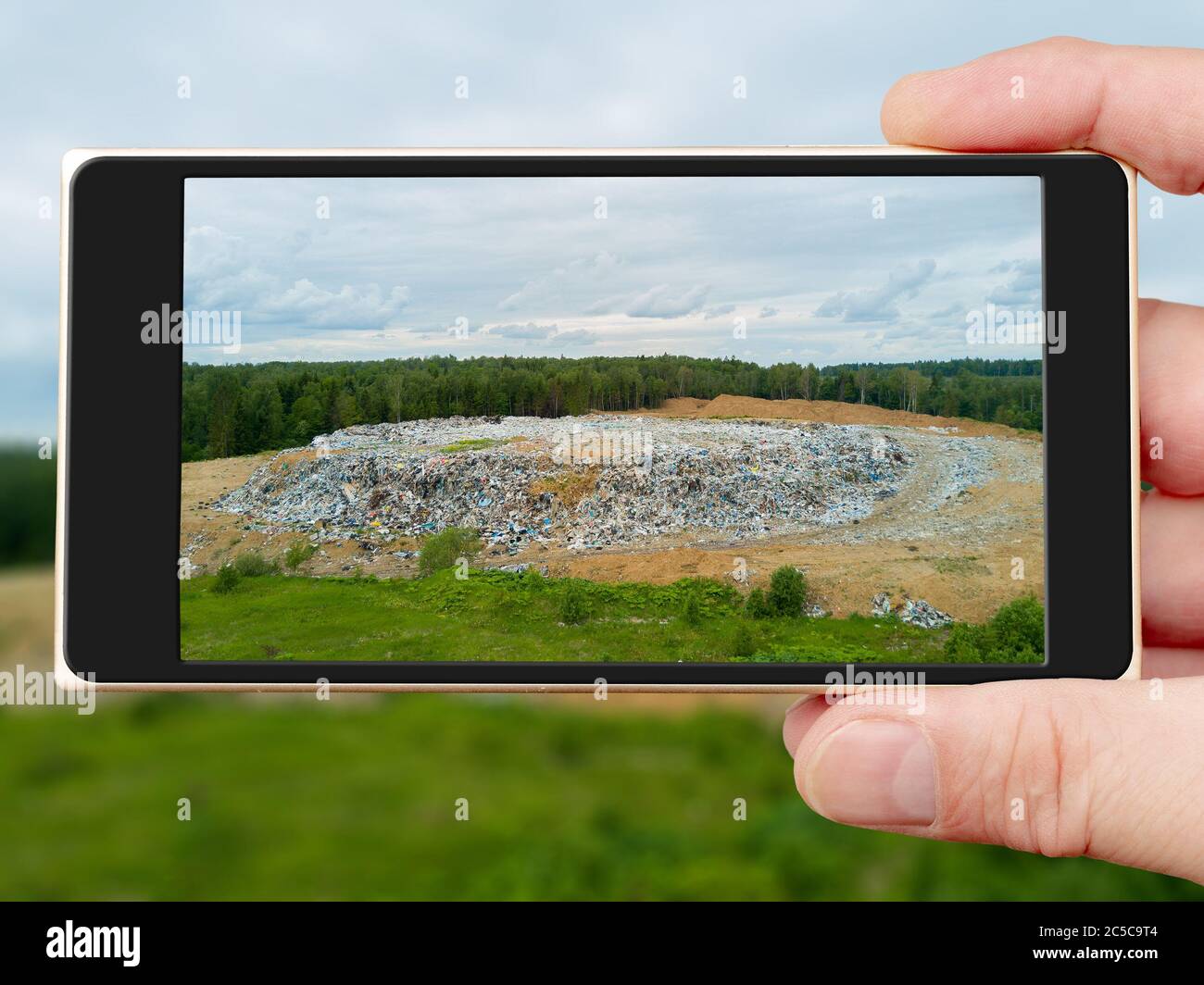 Garbage dump on smartphone screen. Polluting landfill in the forest ...