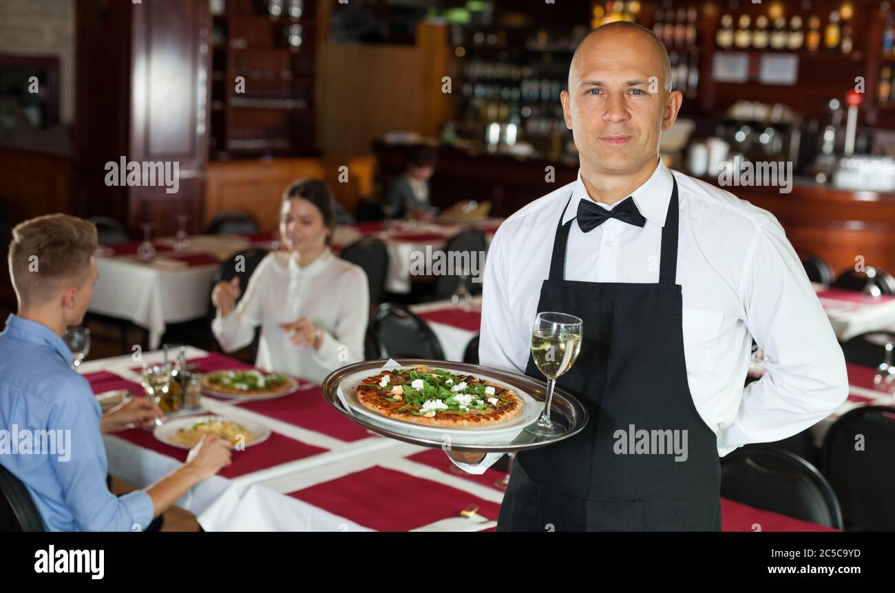 Handsome elegant waiter with serving tray welcoming to restaurant Stock ...
