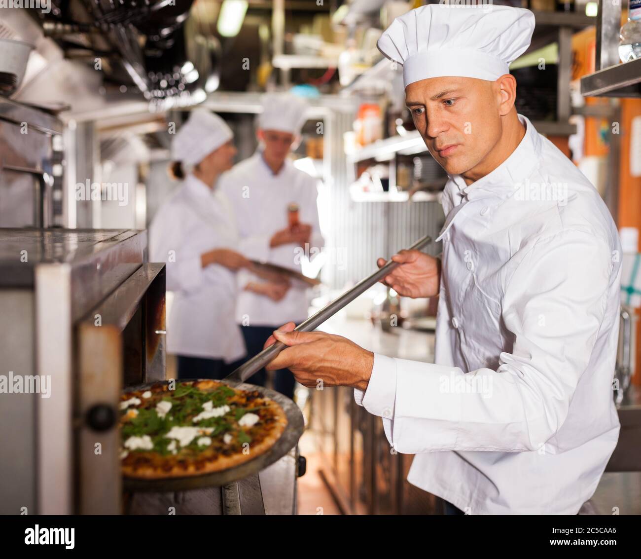 Qualified chef standing near professional oven in modern restaurant ...