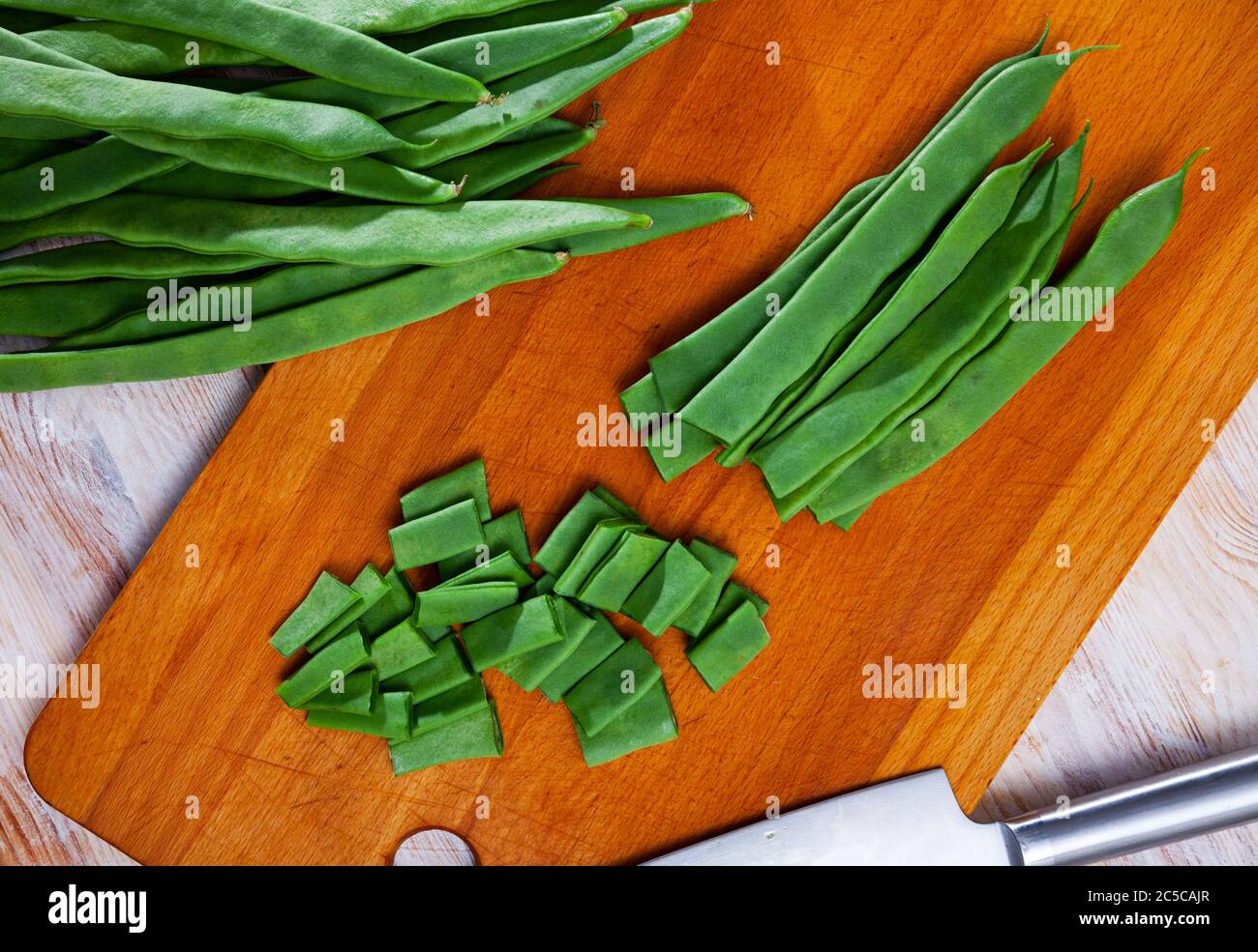 Fresh green beans sliced on wooden cutting board, food preparation ...