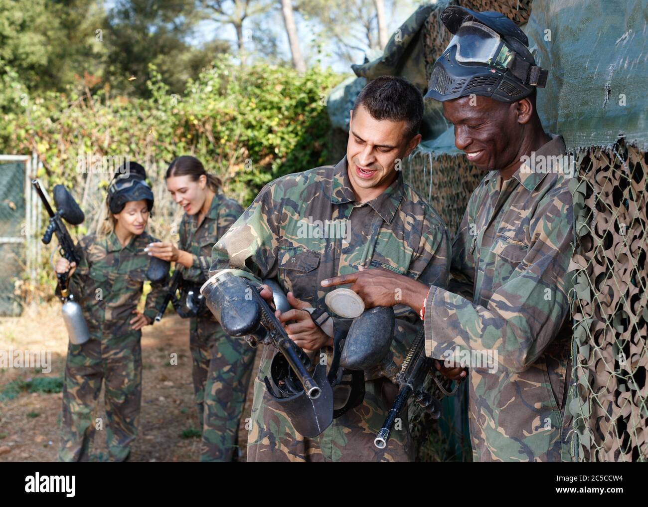 Experienced diligent cheerful paintball player instructing beginner ...