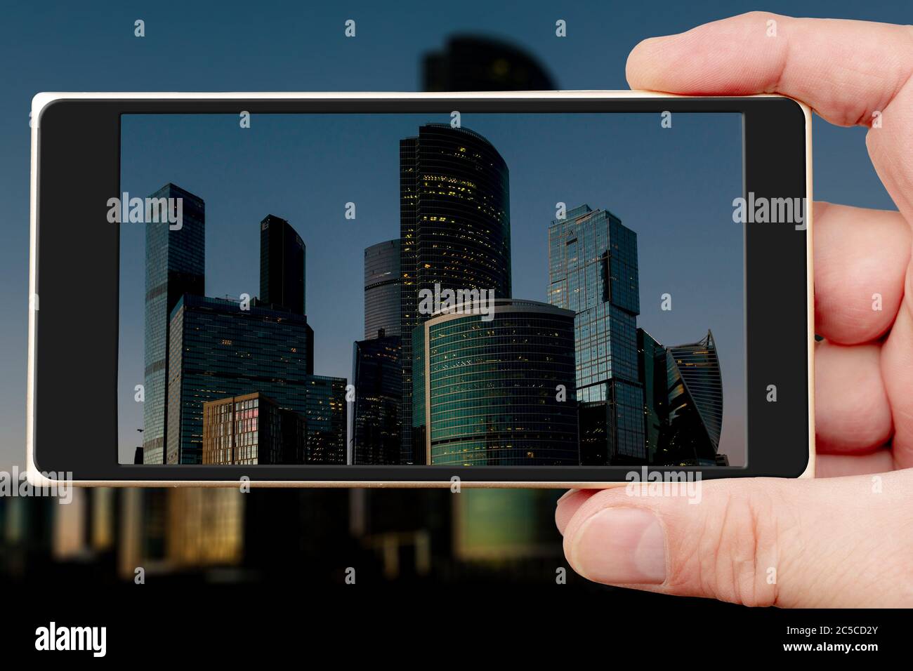 Buildings on smartphone screen. Skyscrapers in sunset light. Lights of ...