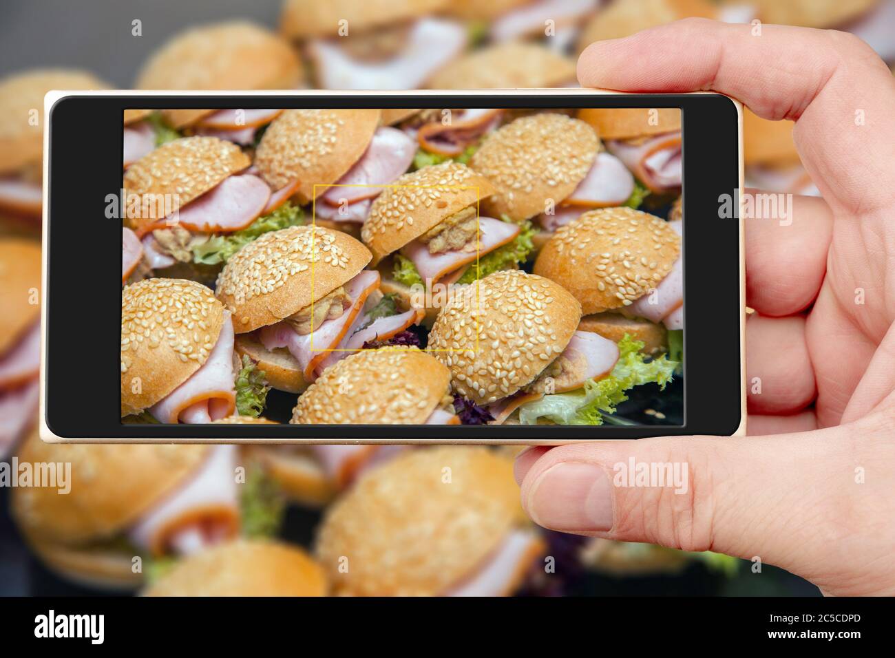 Sandwiches in smartphone screen. Cold appetizers on tray. hamburger ...