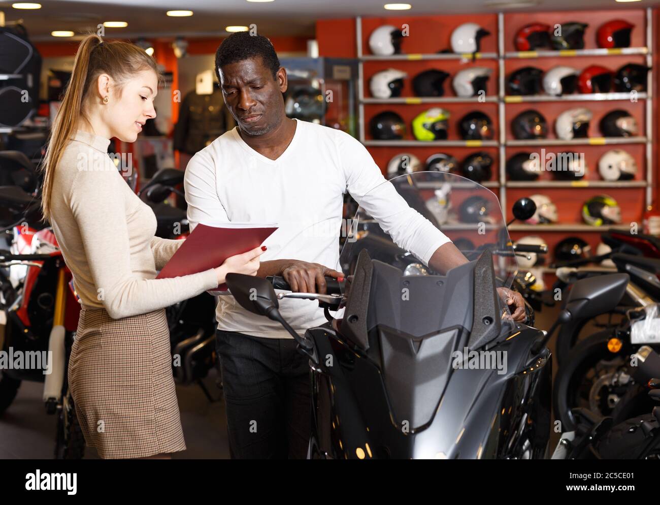 Pretty shopping assistant helping and demonstrating man customer ...