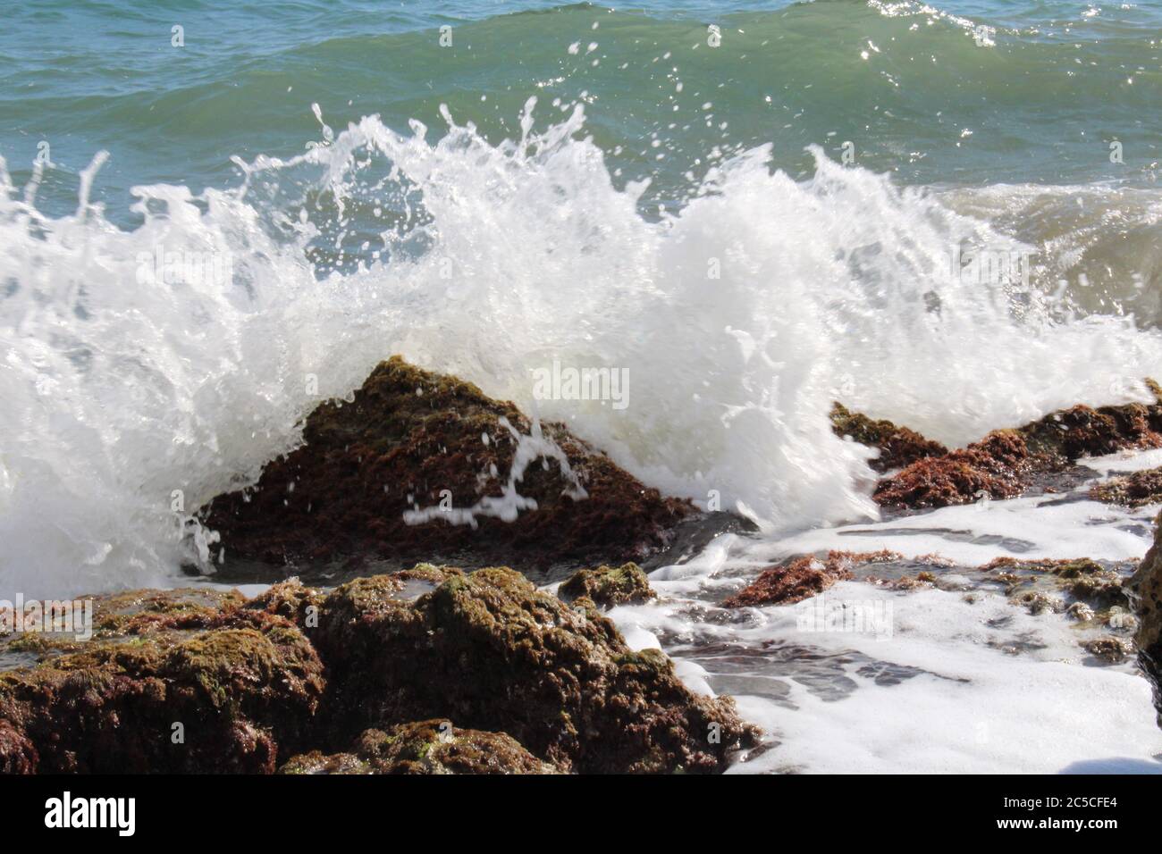 sea water splashes touching the stone on beach Stock Photo - Alamy