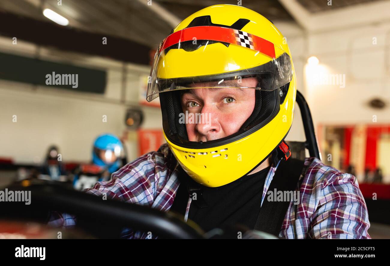 active man and his friends competing on racing cars at kart circuit ...