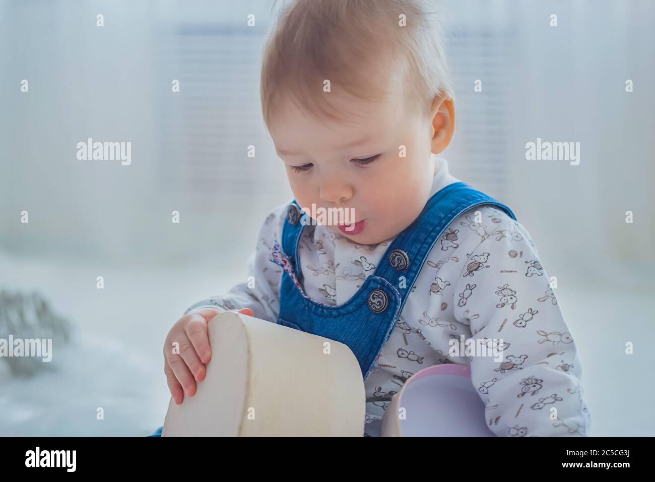 Little boy playing with empty gift box in bright white room at home ...