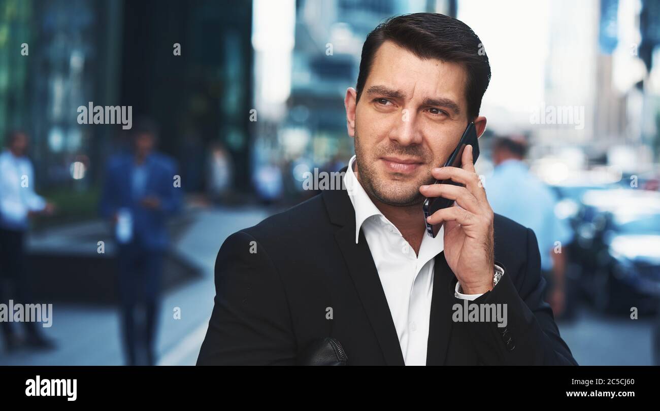 Positive Young Businessman Talking On Smartphone While Looking Away