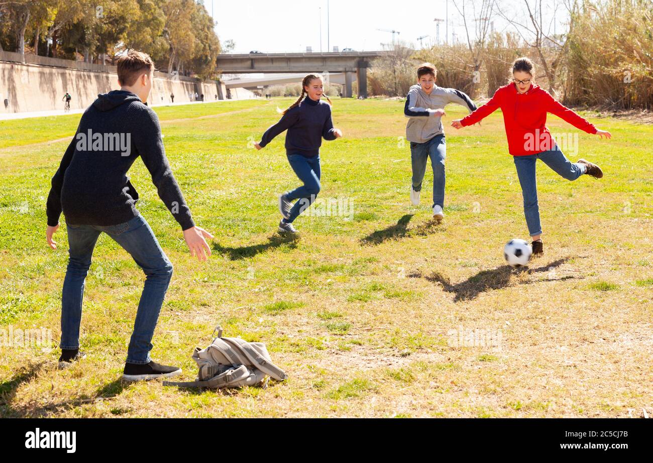 Company of glad teenagers playing football in park Stock Photo - Alamy