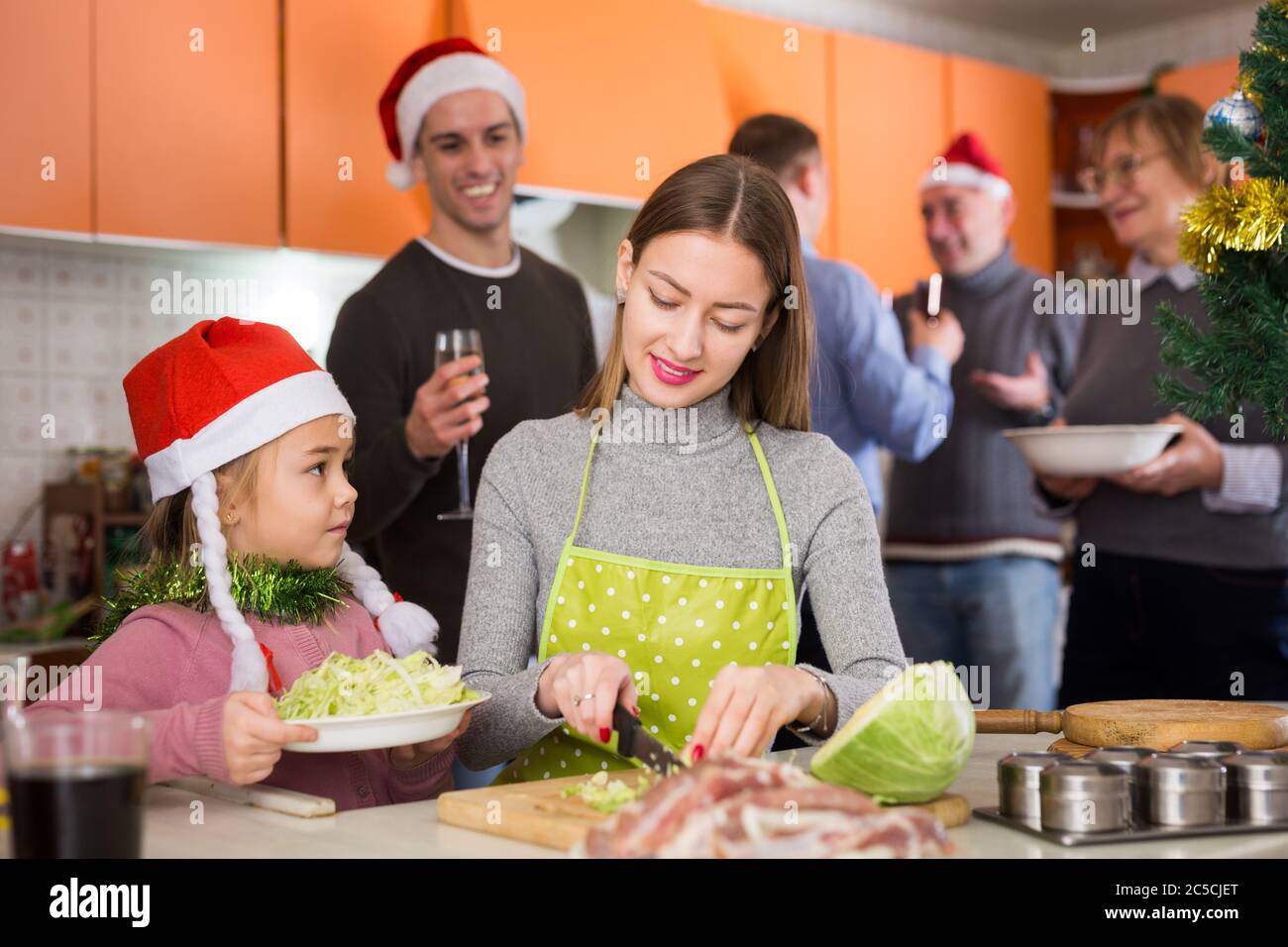Little girl helping young woman making dinner, friendly family ...