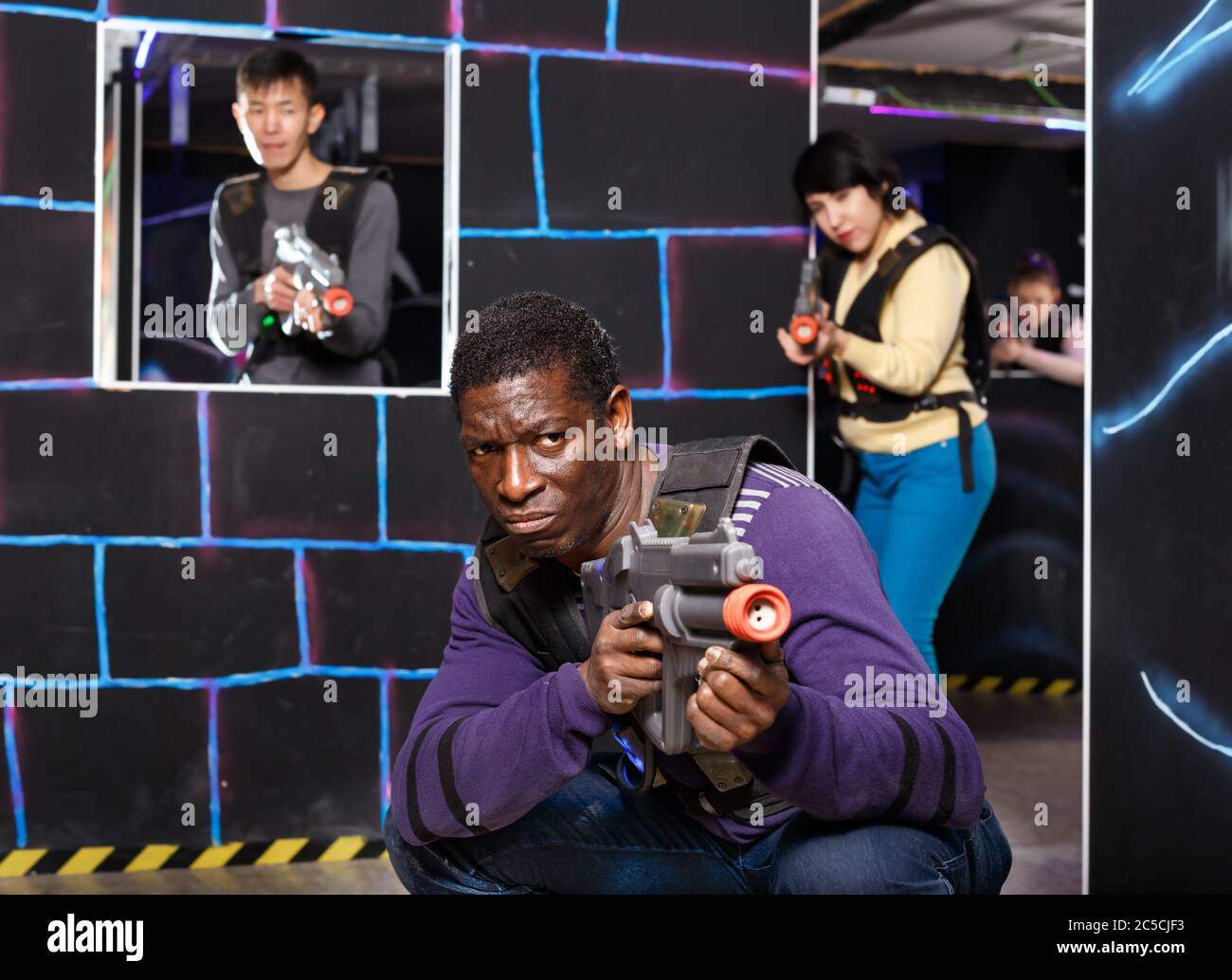 Emotional African man with his laser pistol playing laser tag with ...