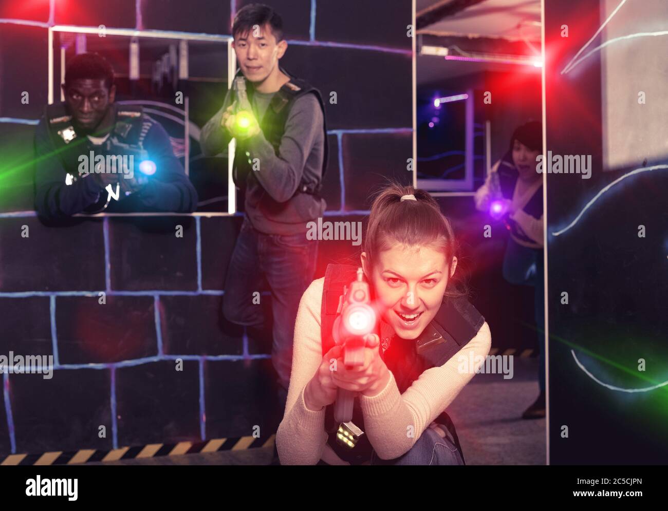 Emotional adult girl with laser pistol playing laser tag with ...