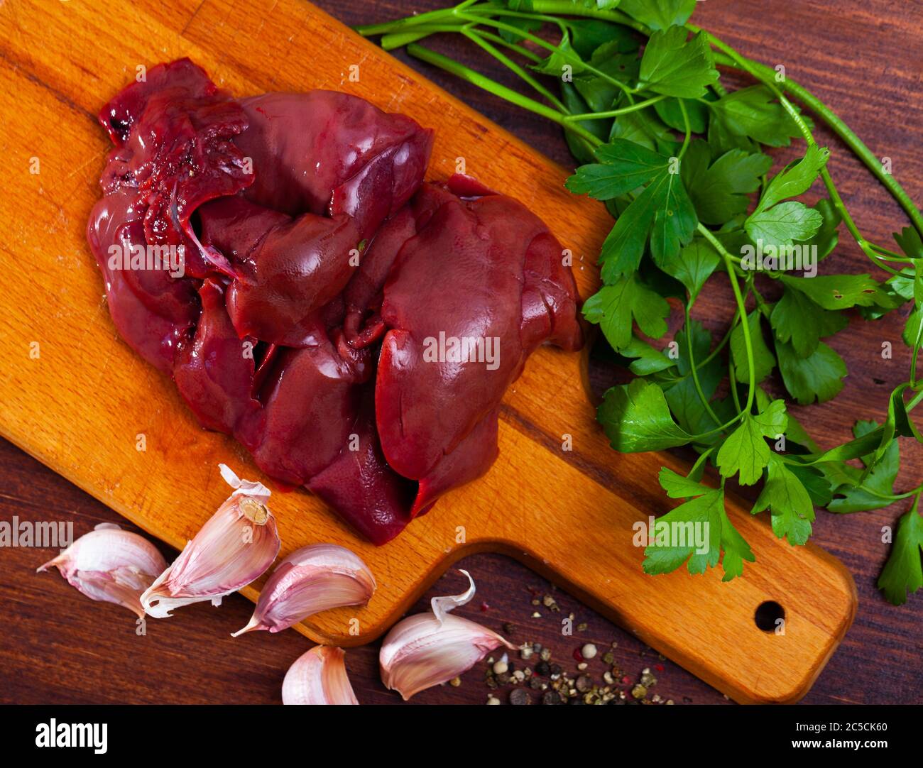 Fresh rabbit liver on wooden background with parsley, garlic and onion ...