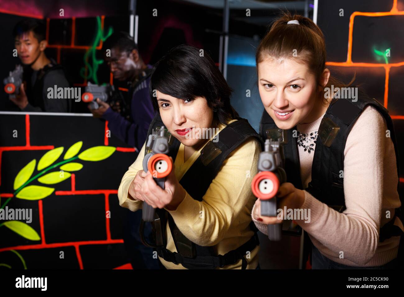 Portrait of two happy emotional female laser tag players having fun in ...