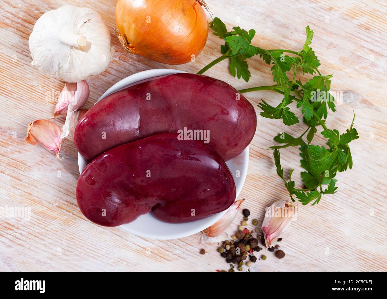 Raw pork kidney with garlic and greens before cooking on table Stock ...