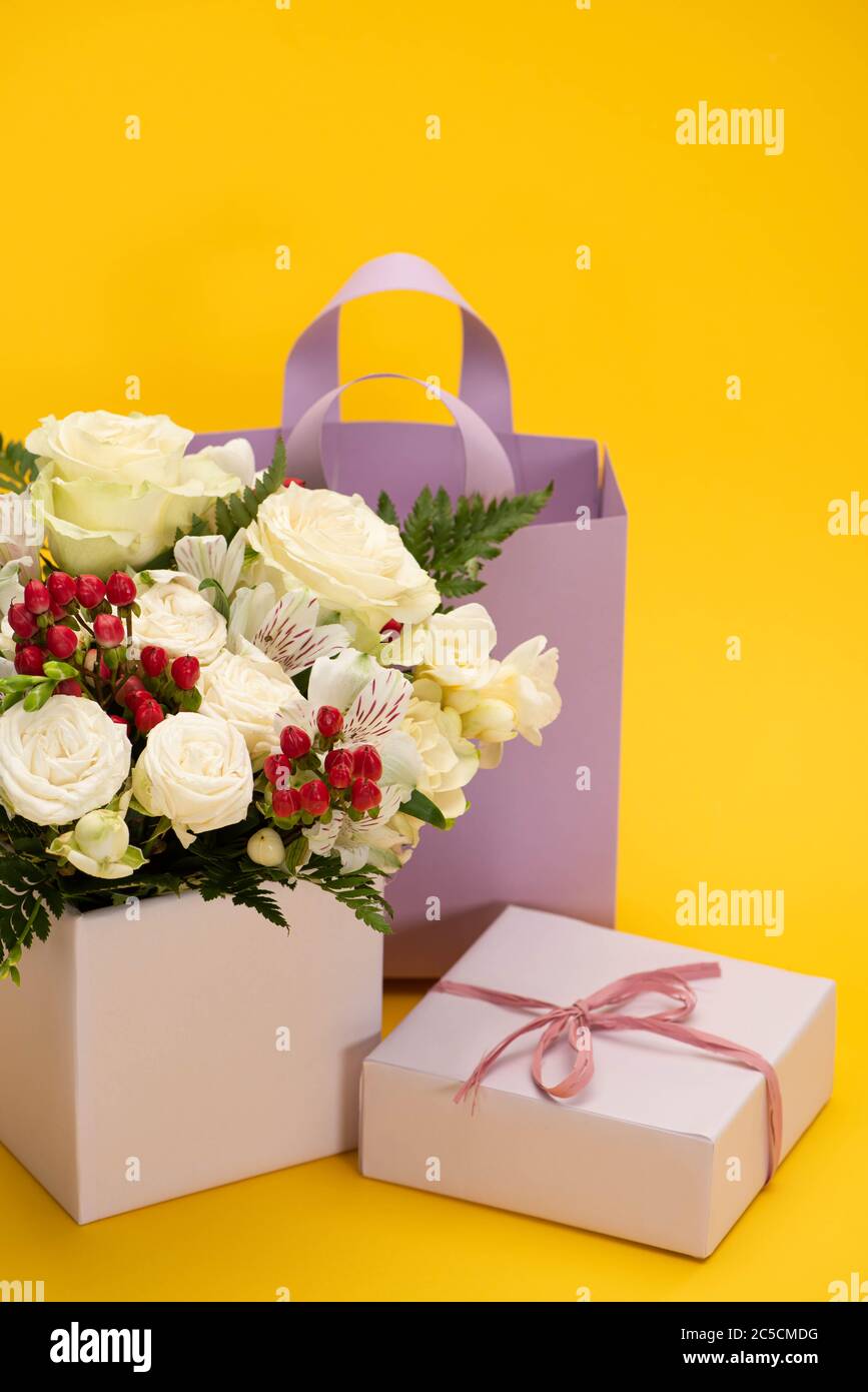 spring fresh bouquet of flowers in festive gift box near paper bag on ...