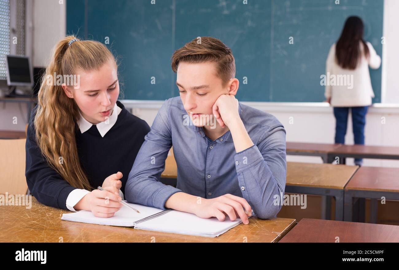 Positive girl student explaining study material to her classmate in ...