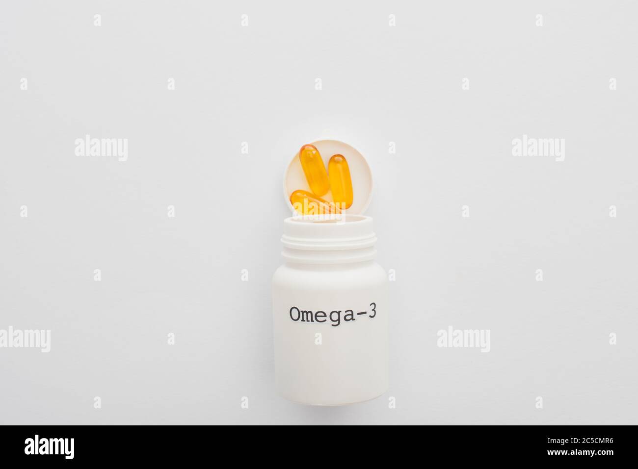 Top view of opened container with omega-3 capsules on white background ...
