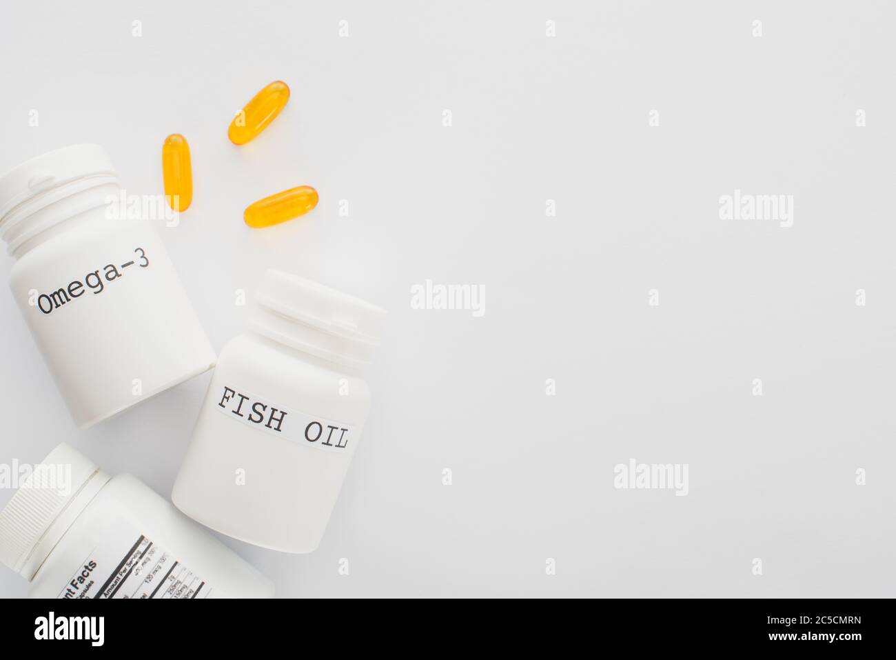 Top view of containers with fish oil and omega-3 lettering near yellow ...