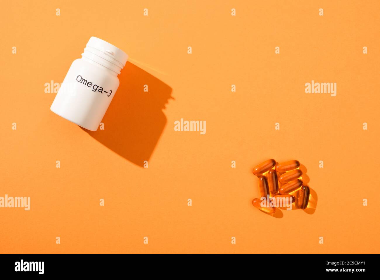 Top view of container with omega-3 lettering and capsules on orange ...